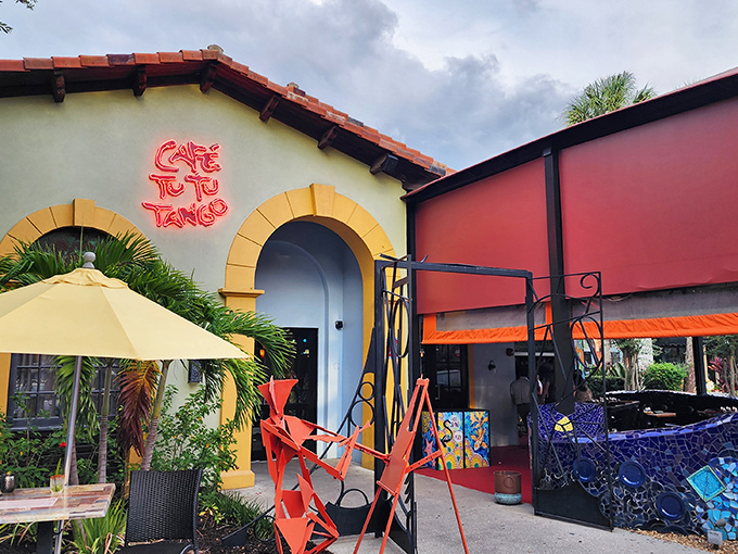 The vibrant exterior of Café Tu Tu Tango beckons with its Spanish-inspired architecture and neon signage – like a colorful oasis in Orlando's tourist corridor.