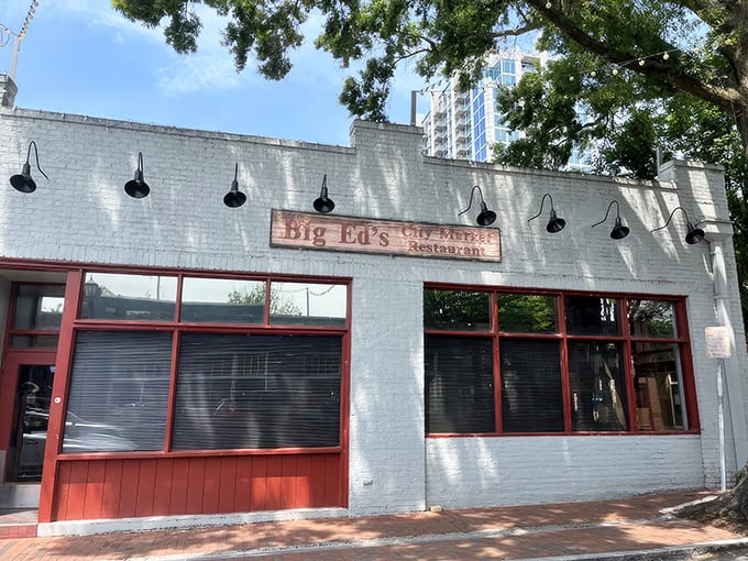 The unassuming white brick exterior of Big Ed's City Market Restaurant, where culinary magic happens behind those red-trimmed windows.