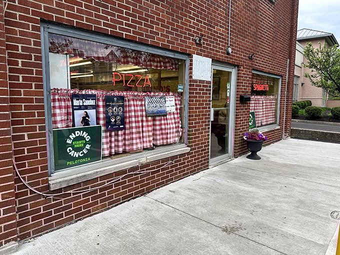The unassuming brick exterior of Rubino's Pizza, with those iconic red-checkered curtains, is like finding a secret doorway to pizza paradise.