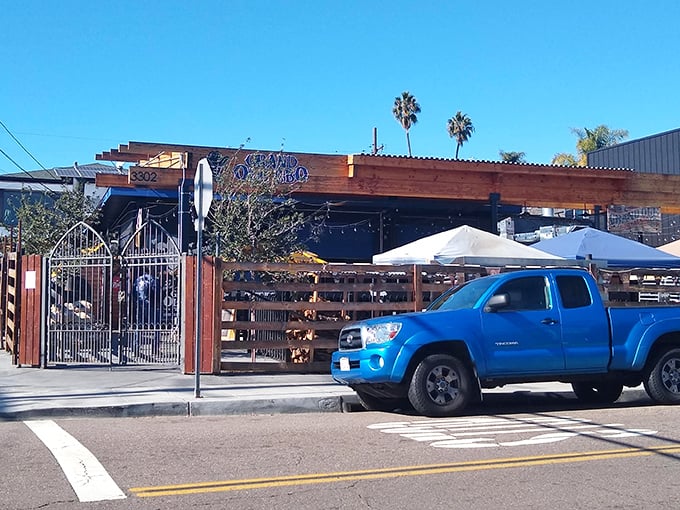 The rustic wooden facade of Grand Ole BBQ beckons like a smoke signal to barbecue pilgrims. Those yellow umbrellas aren't just for show—they're holding space for your BBQ dreams.