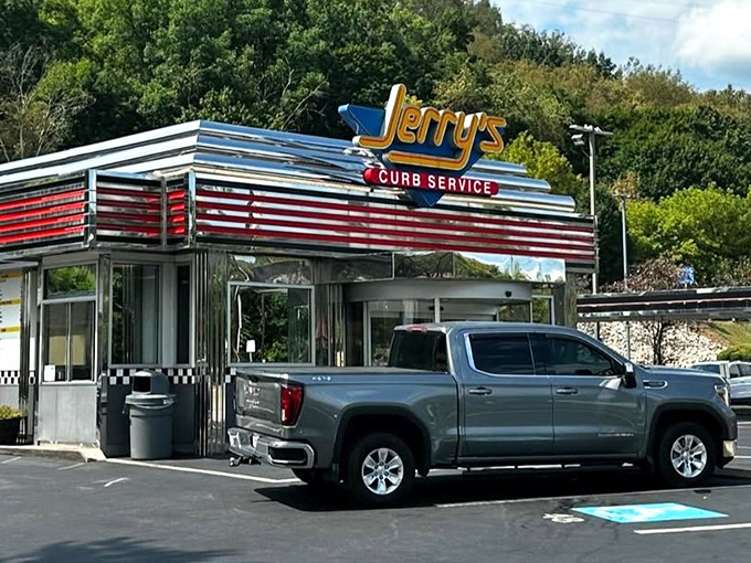 The gleaming chrome and neon of Jerry's Curb Service isn't just a restaurant sign—it's a time machine to when drive-ins ruled and dinner came with a side of nostalgia.