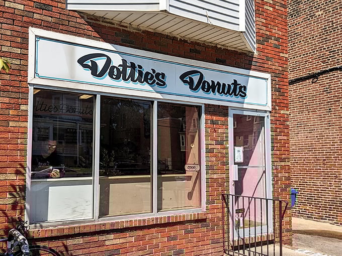 The unassuming brick storefront of Dottie's Donuts in West Philly, where vegan pastry magic happens daily behind that retro blue sign.