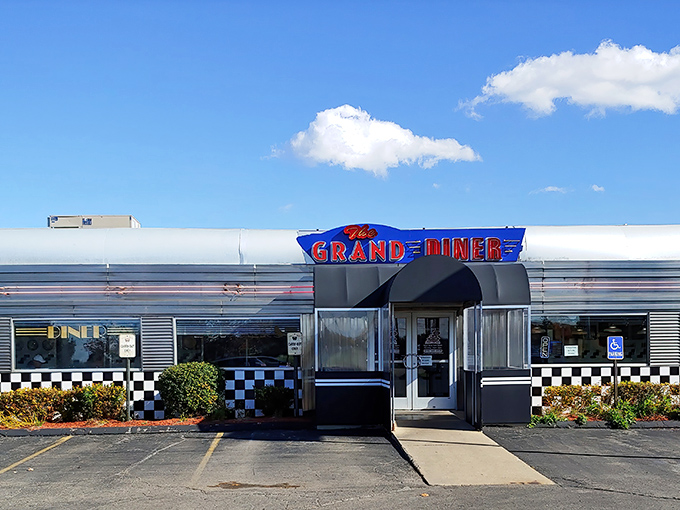 The gleaming silver exterior of The Grand Diner stands like a time machine to the golden age of roadside Americana. That checkered trim promises good things await inside.