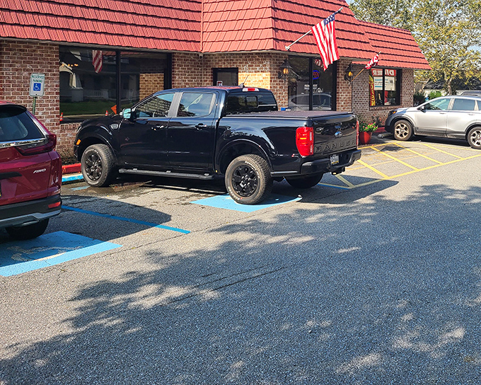 Classic Americana at its finest – a brick exterior with a welcoming bench, vibrant flower pots, and that iconic red roof that practically whispers "come hungry, leave happy."