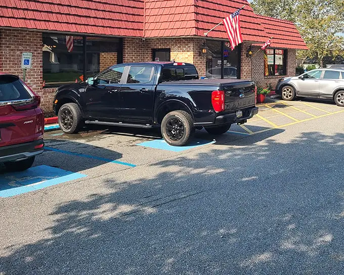 Classic Americana at its finest – a brick exterior with a welcoming bench, vibrant flower pots, and that iconic red roof that practically whispers "come hungry, leave happy."