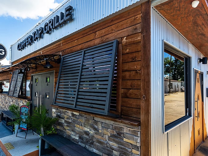 The rustic-meets-modern exterior of Copper Tap Grille beckons with its corrugated metal, warm wood, and stone accents—architectural proof that the best flavors often hide in unassuming packages.