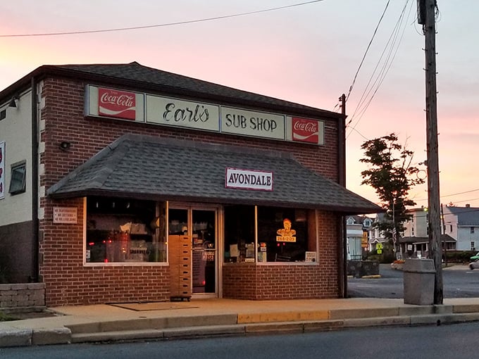 Earl's Sub Shop at sunset – where the humble brick exterior and vintage Coca-Cola signs promise authentic deliciousness that transcends the modest surroundings.