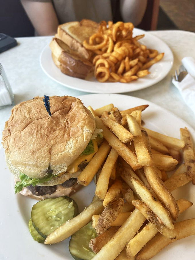 The burger arrives with zero pretension and maximum satisfaction, surrounded by a golden regiment of hand-cut fries standing at delicious attention.