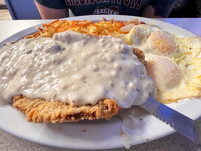 Chicken fried steak smothered in gravy with crispy hash browns—the kind of breakfast that makes you want to cancel your other meals for the day.
