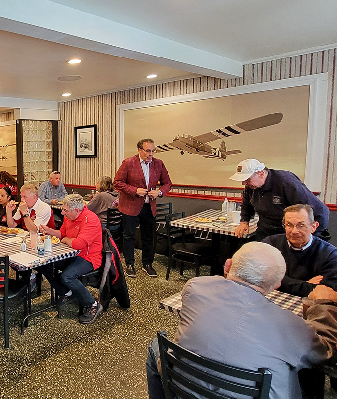 The aviation theme continues inside with vintage airplane art. Notice the locals deep in conversation—this isn't just a restaurant, it's a community hub. 