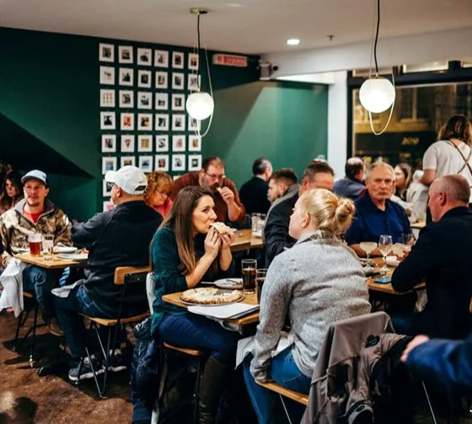 The universal expression of pizza joy—that moment when the first bite exceeds all expectations and conversation momentarily ceases.