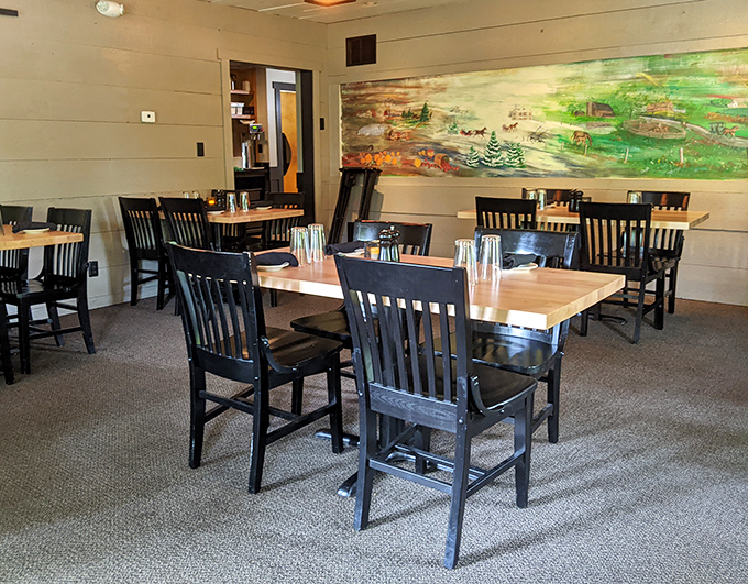 Simple wooden tables and chairs against cream walls with rustic artwork – no distractions from the main event on your plate.
