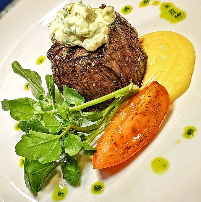 Even the steak gets the coastal treatment, topped with herb butter and served alongside a half lobster tail—surf and turf perfection on a pristine plate.