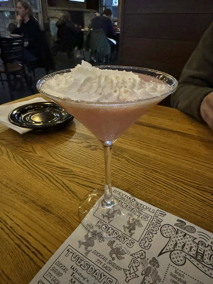 A martini that doesn't just arrive—it makes an entrance. Pink, proud, and topped with enough whipped cream to make a barista jealous.