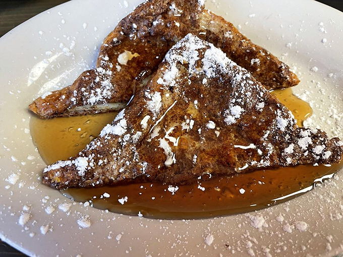 French toast that would make actual French people reconsider their citizenship. Dusted with powdered sugar and swimming in syrup—breakfast as dessert is always the right choice.