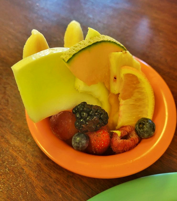 Nature's candy arranged in a cheerful orange bowl—a fresh fruit medley that somehow tastes better here than from your own refrigerator.