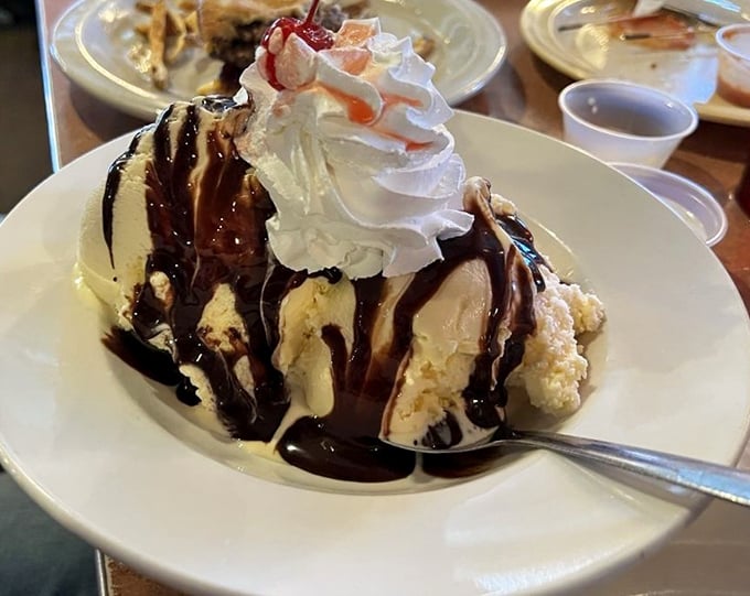 Ice cream sundae architecture at its finest—where hot fudge cascades down vanilla mountains creating the kind of dessert worth driving miles for.