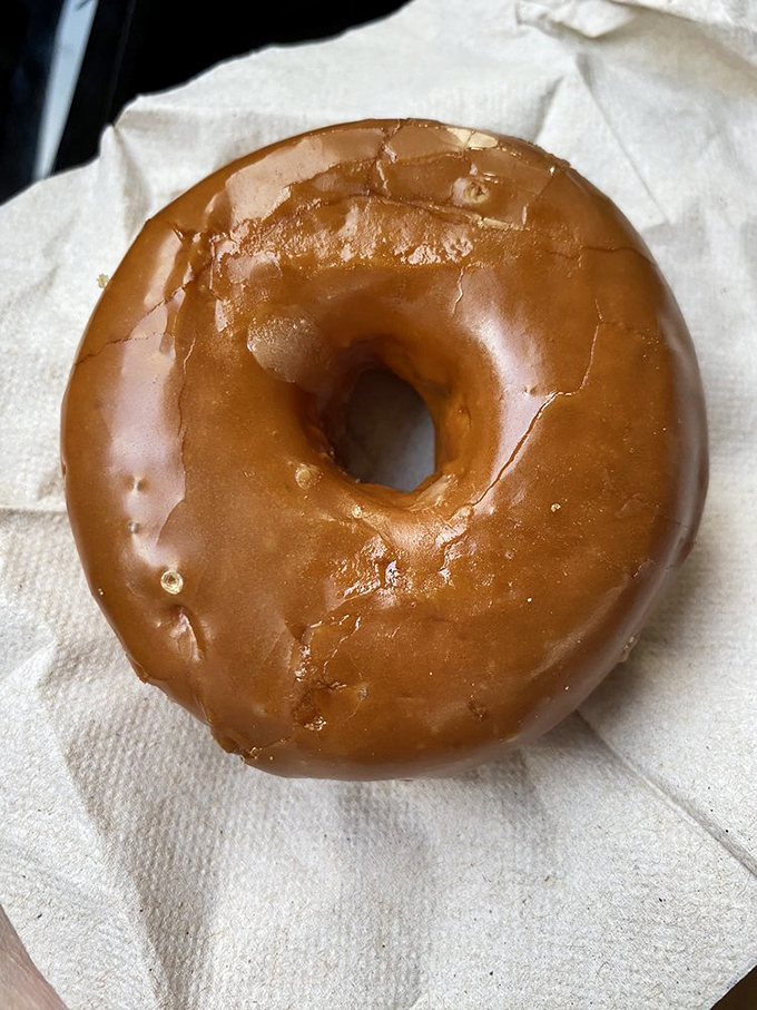 A perfectly executed maple glazed donut on humble paper—sometimes the simplest pleasures deliver the most profound satisfaction.