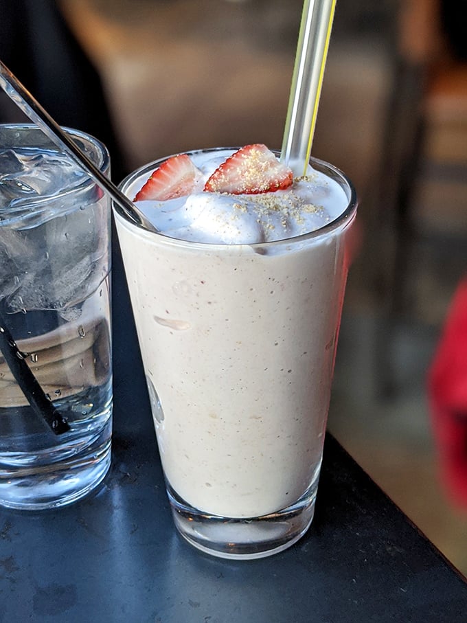 A milkshake that understands the importance of texture and garnish. That strawberry isn't just decoration—it's a promise of the fresh flavors waiting below.