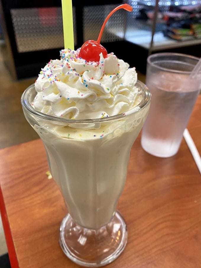 A vanilla milkshake topped with whipped cream, sprinkles, and a cherry—proof that sometimes the classics need no improvement, just proper execution.