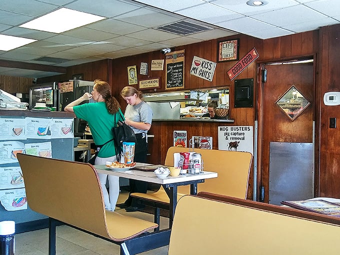 The kitchen pass-through where magic happens. Those "Kiss My Grits" signs aren't just decoration – they're a philosophy.
