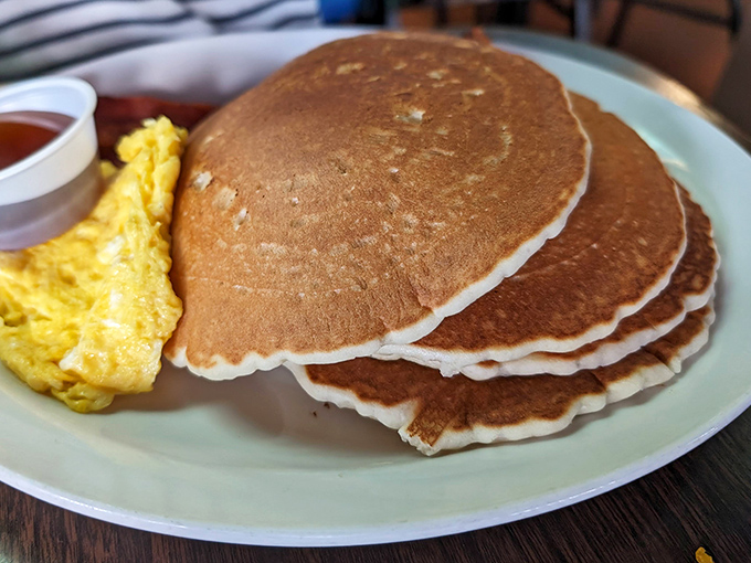 Pancakes so perfectly golden they belong in Fort Knox, served alongside eggs that practically glow with morning promise.