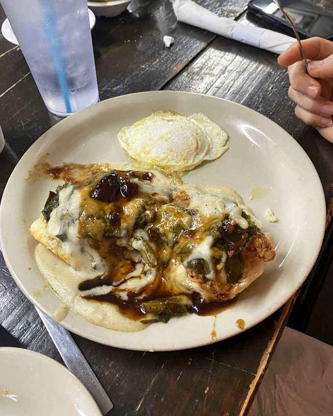 A plate that whispers "slow down" with every bite—tender meat under a blanket of gravy alongside a sunny-side egg.