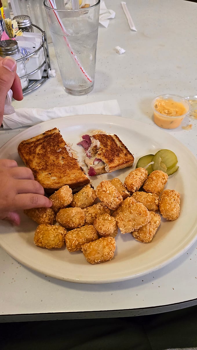 Half-eaten Reuben with tater tots—the only tragedy here is that someone had the willpower to stop eating this masterpiece midway.