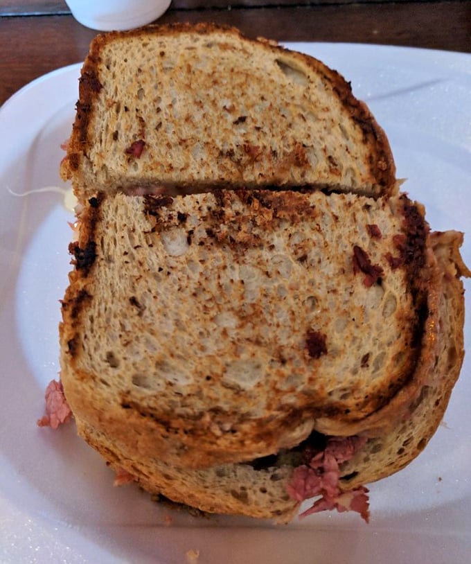 The Reuben sandwich – where toasty rye bread, tender corned beef, and tangy sauerkraut create a holy trinity of deli perfection. Worth every napkin you'll need.
