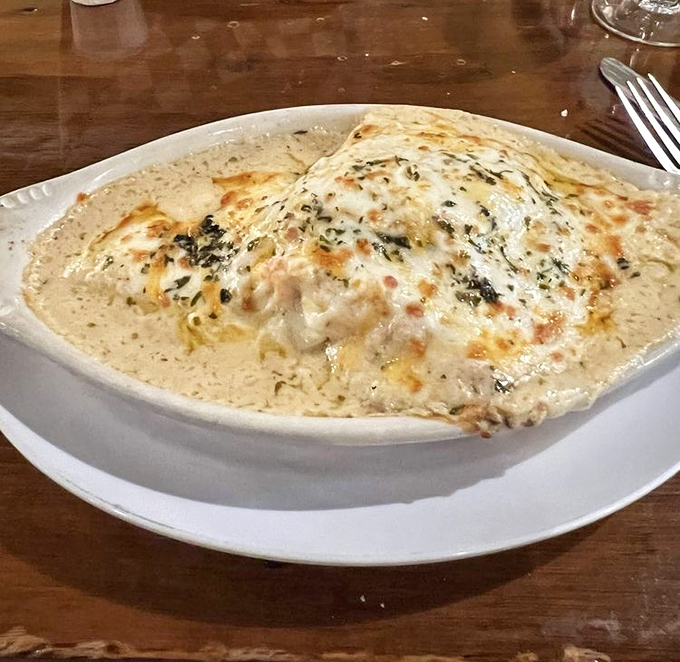This seafood manicotti doesn't just sit on the plate—it lounges luxuriously in cream sauce like it's at a five-star spa for pasta.