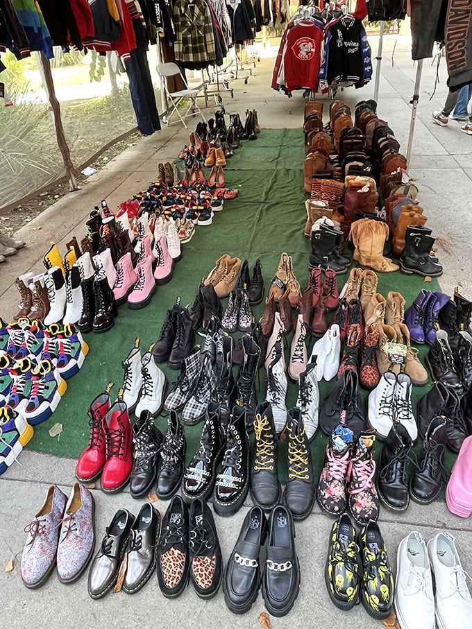 A boot lover's paradise spread across green canvas – where Doc Martens, cowboy boots, and platform shoes create a footwear United Nations.