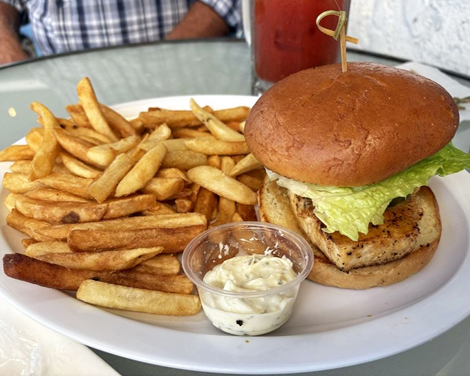 A sandwich that requires both hands and your full attention. Those fries aren't a side dish—they're co-stars in this plate's delicious drama.