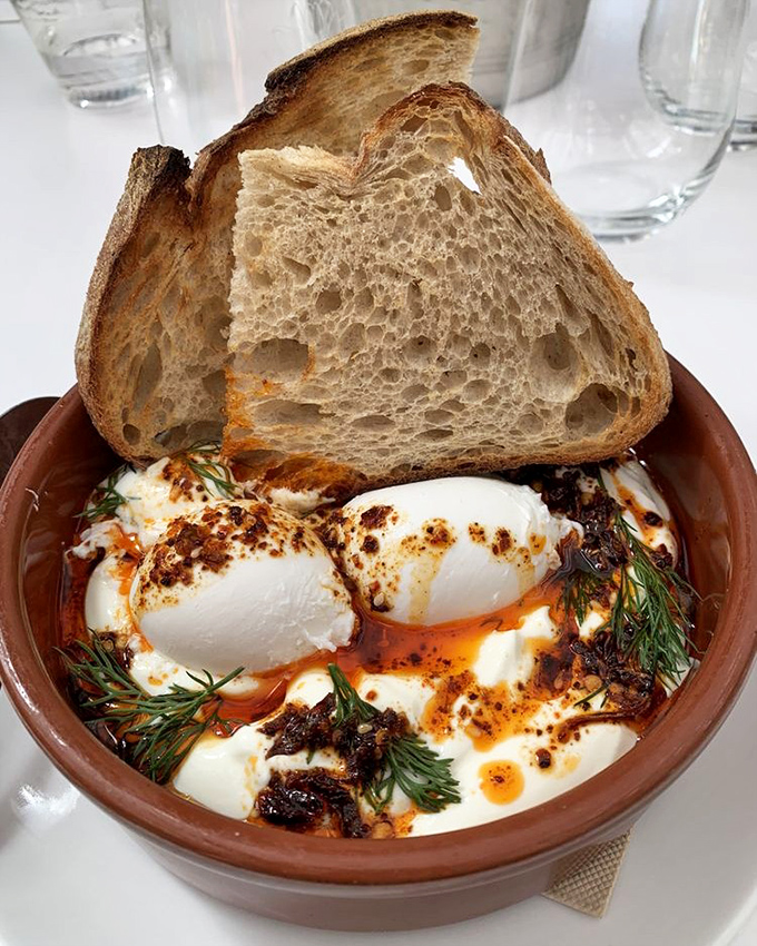 Turkish eggs—where yogurt meets poached eggs in a terra cotta hot tub of chili oil. Bread stands by for necessary dipping operations.