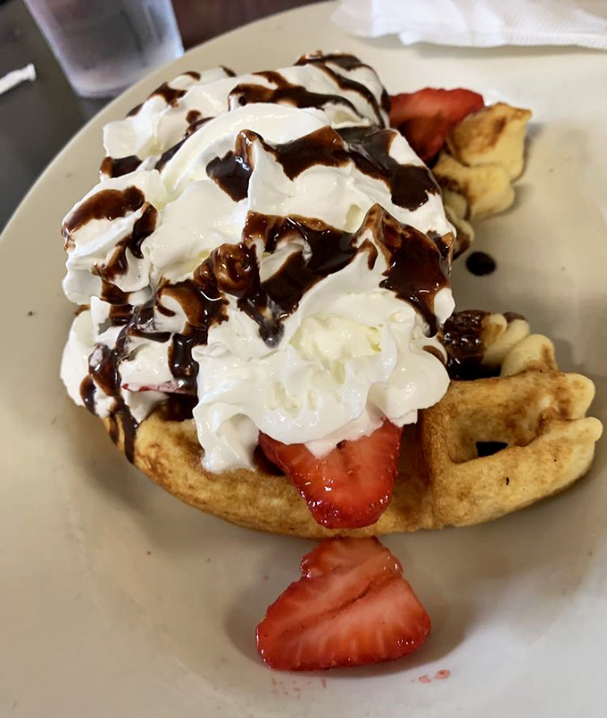 A waffle that's clearly showing off for the camera. With whipped cream, strawberries, and chocolate, it's basically breakfast dessert—and that's perfectly okay.