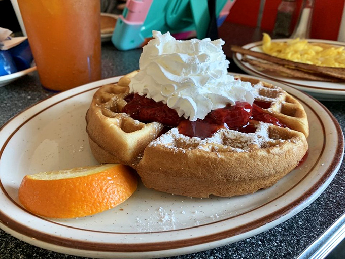 Waffle perfection crowned with strawberries and whipped cream – breakfast that thinks it's dessert, and nobody's complaining.