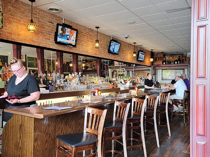 The bar area balances classic charm with modern comfort. Wine bottles stand at attention, ready to complement whatever culinary adventure you choose.