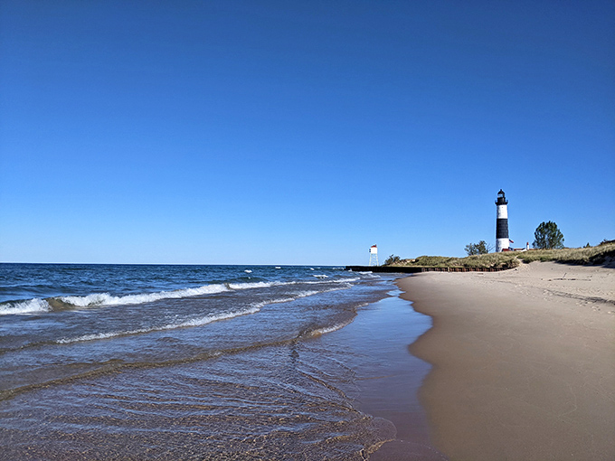 Not just any beach—this is where Lake Michigan's waves meet pristine sand, with another lighthouse standing guard in the distance.