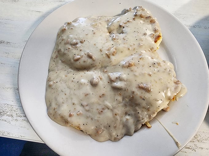 Beneath this creamy blanket of sausage gravy lies a biscuit experiencing its best life. Southern comfort that needs no translation.