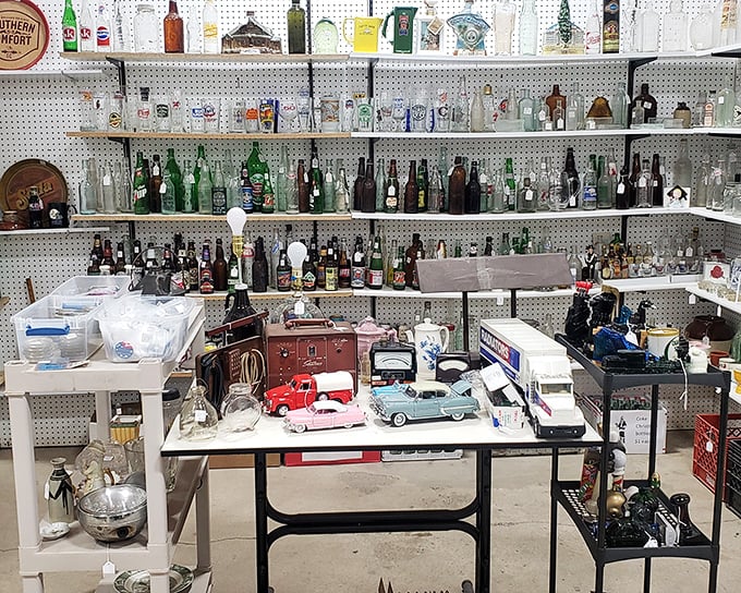 A bottle collector's dream wall—where vintage Coca-Cola meets forgotten local brews, with toy cars parked below like a miniature drive-in.