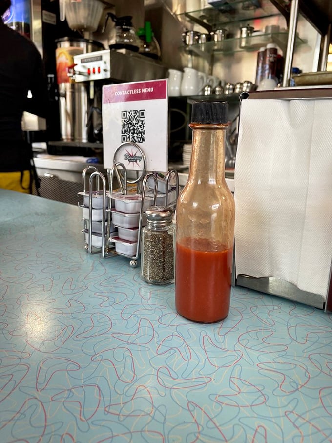 The holy trinity of diner condiments—hot sauce, pepper, and those little creamers that somehow make you feel like you're getting away with something.