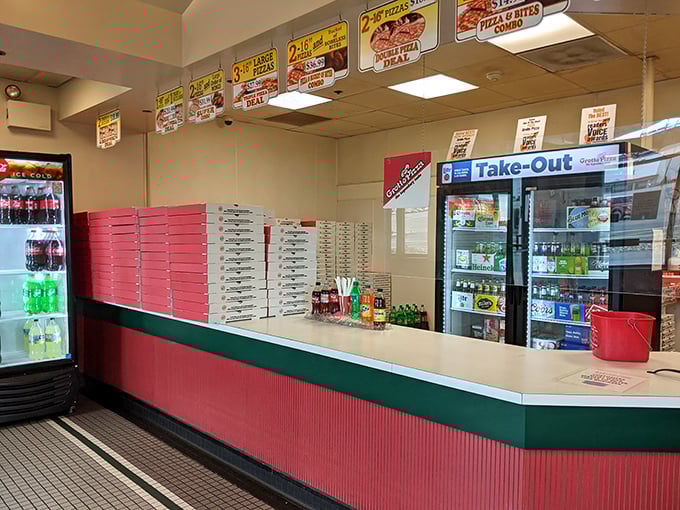 The take-out counter where pizza dreams come boxed. Those stacked red boxes hold the promise of dinner table happiness.