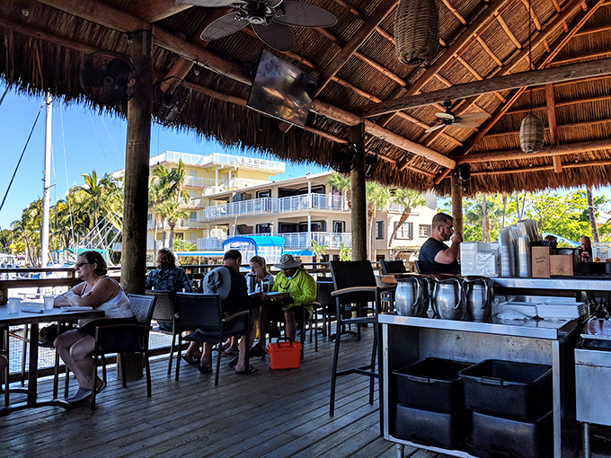 Under the thatched tiki roof, diners enjoy the quintessential Keys experience—cold drinks, ocean breezes, and the feeling that Monday is very far away.