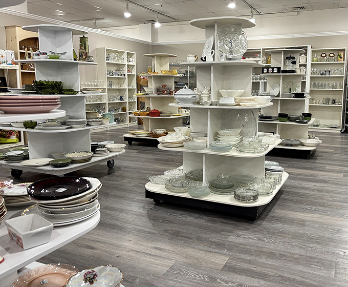The dishware section gleams with possibility—crystal, china, and everyday plates arranged like a foodie's dream garage sale.