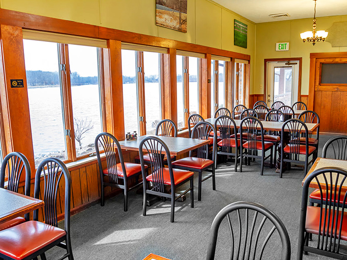 Red chairs pop against panoramic lake views in this dining room where every table feels like the best seat in the house.