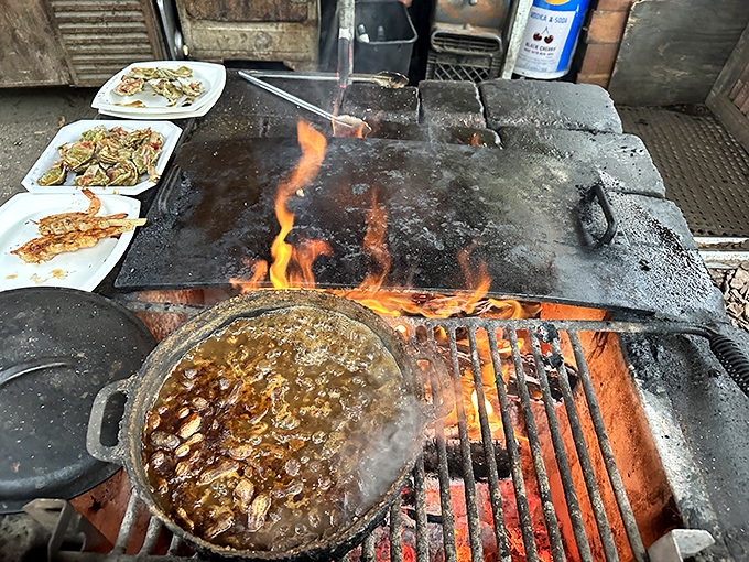 The open flame kitchen isn't just cooking food – it's performing culinary theater where smoke and fire are essential supporting characters.