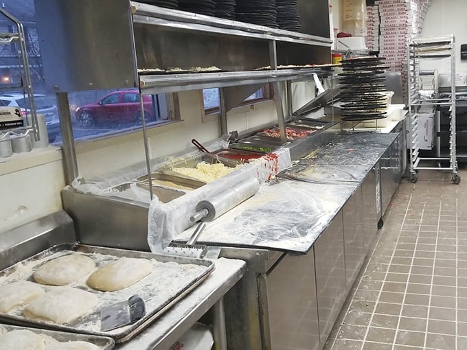 The pizza assembly line reveals the secret to consistency—fresh dough waiting to be transformed into the pies that put Alibi on the map.