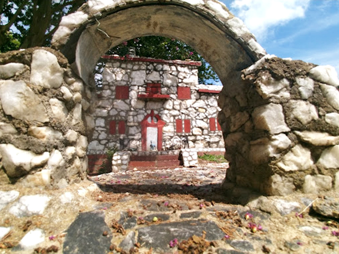 This stone arch frames a perfect view of a miniature mansion. It's like a portal to a parallel universe where everything is perfectly crafted, just smaller.