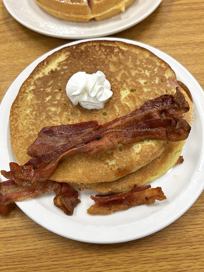 Pancakes wearing bacon like a medal of honor. That dollop of whipped butter melting into golden perfection is breakfast poetry.