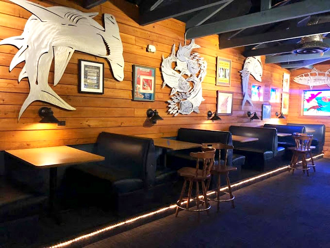 Metal fish sculptures swim across wooden walls while comfortable booths invite you to settle in. Maritime meets cozy in this dining nook.