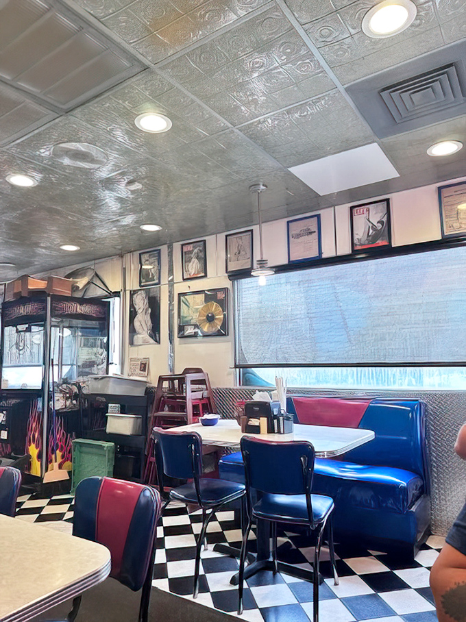 Blue and red vinyl booths pop against metallic walls, while framed memorabilia creates a museum of Americana where the admission price is just a cup of coffee.